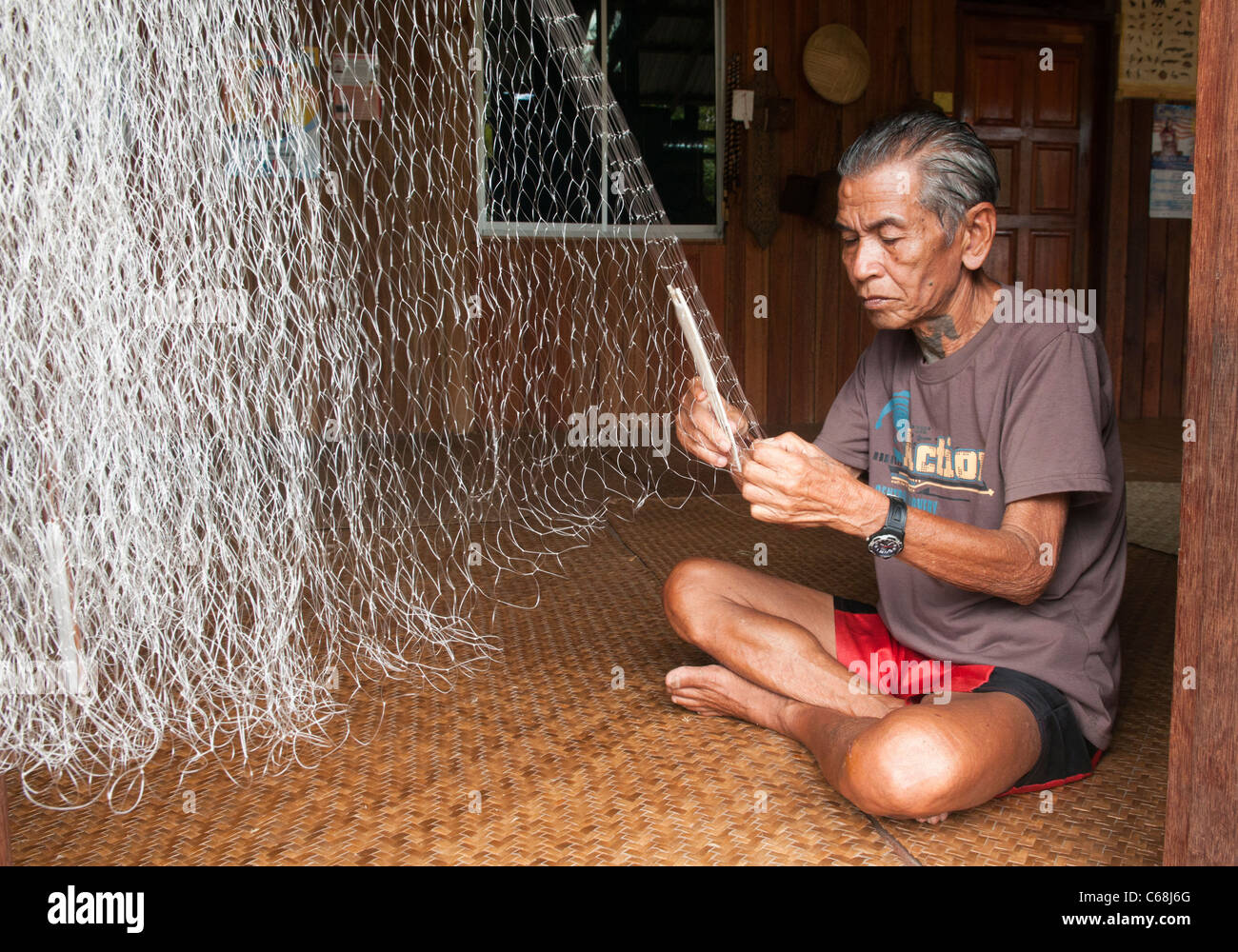 Iban longhouse chief mends his fishing nets at the Nanga Sumpa ...