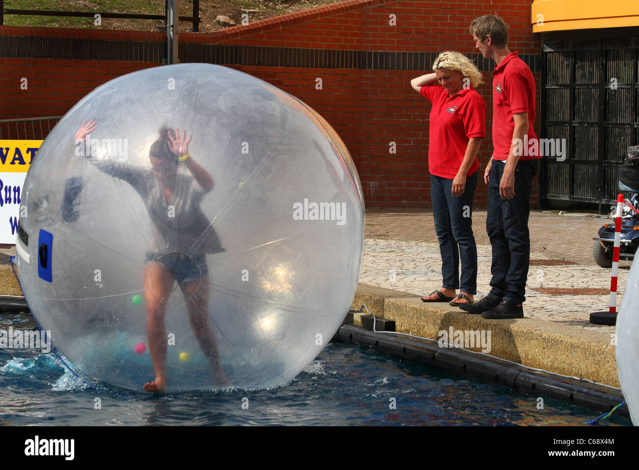 People in clear plastic bubbles running on water in amusement arcade at ...