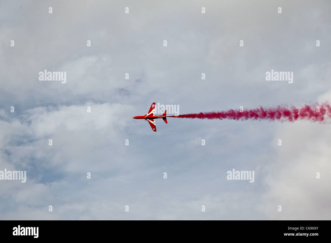 Red Arrow flies against cloudy sky with red smoke Stock Photo - Alamy