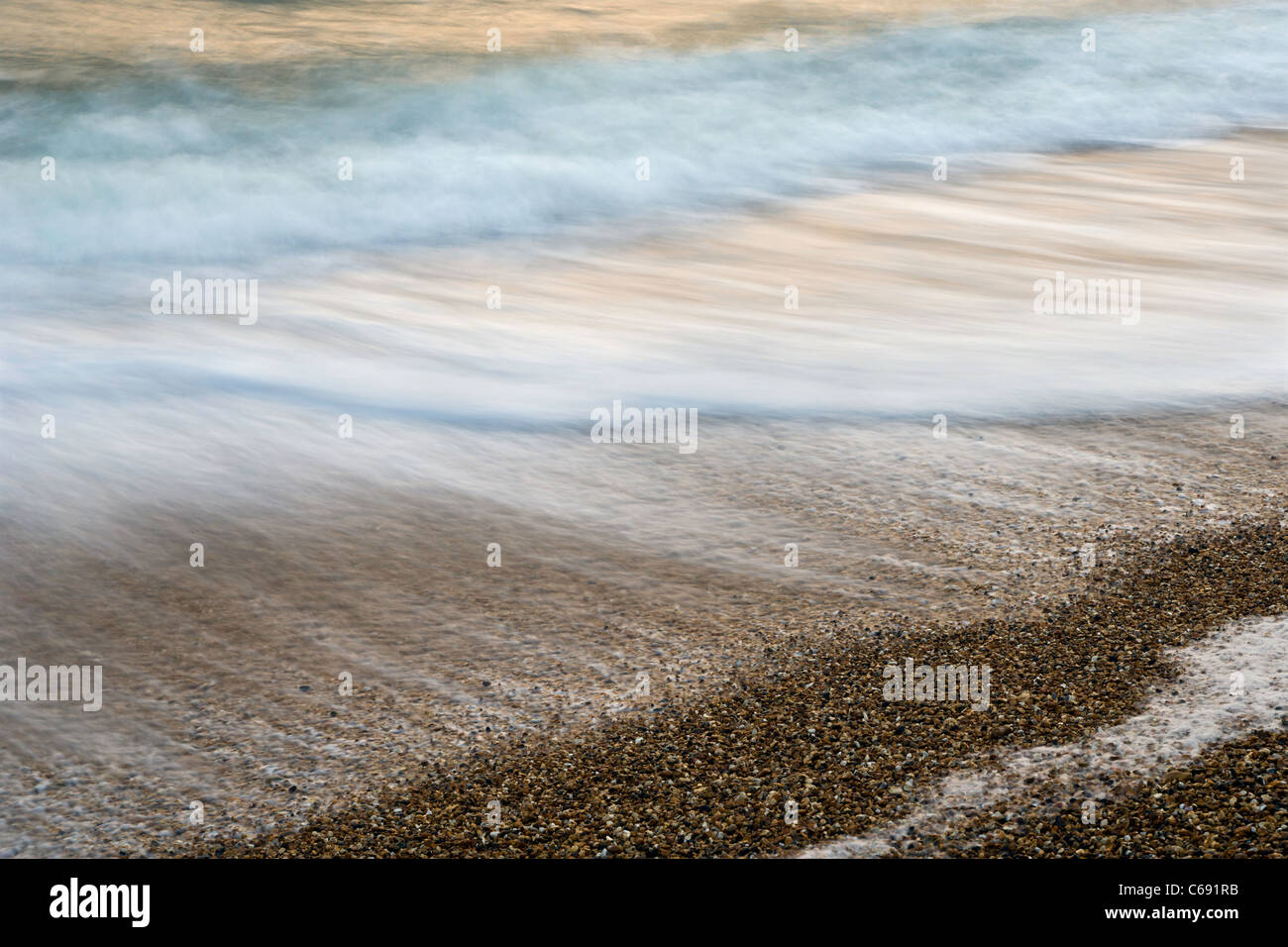 Waves on a pebble beach with sunlight reflected off them Stock Photo ...