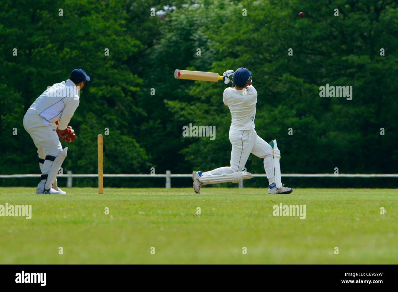 A cricket batsman playing a pull shot towards the boundary in a cricket ...