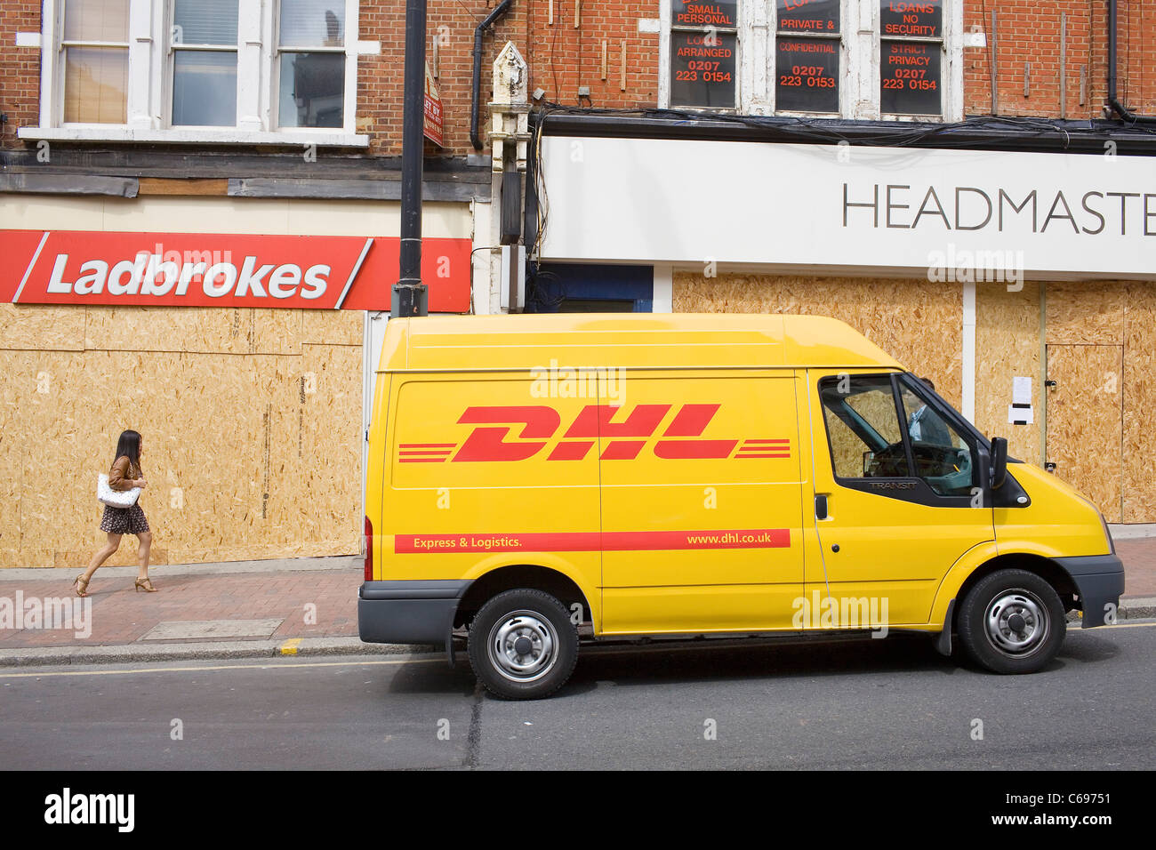A woman walks past boarded up shops in Clapham damaged in the August ...