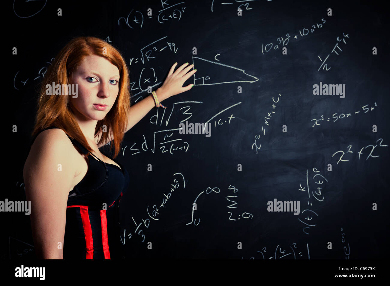 Redhead woman point to formulas on a blackboard Stock Photo - Alamy