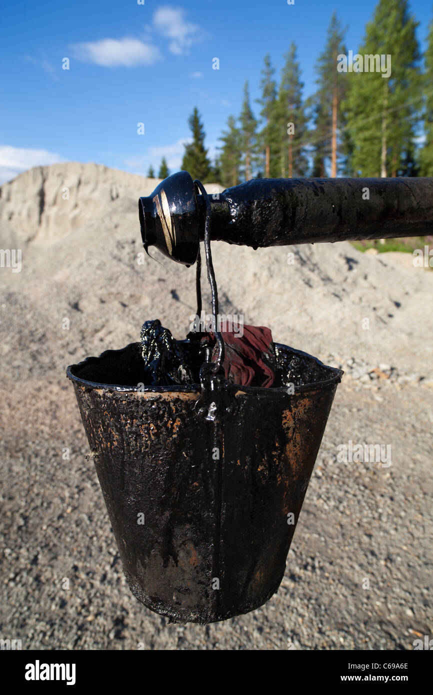 Metal bucket filled with pitch dripping from pipe's end , Finland Stock ...