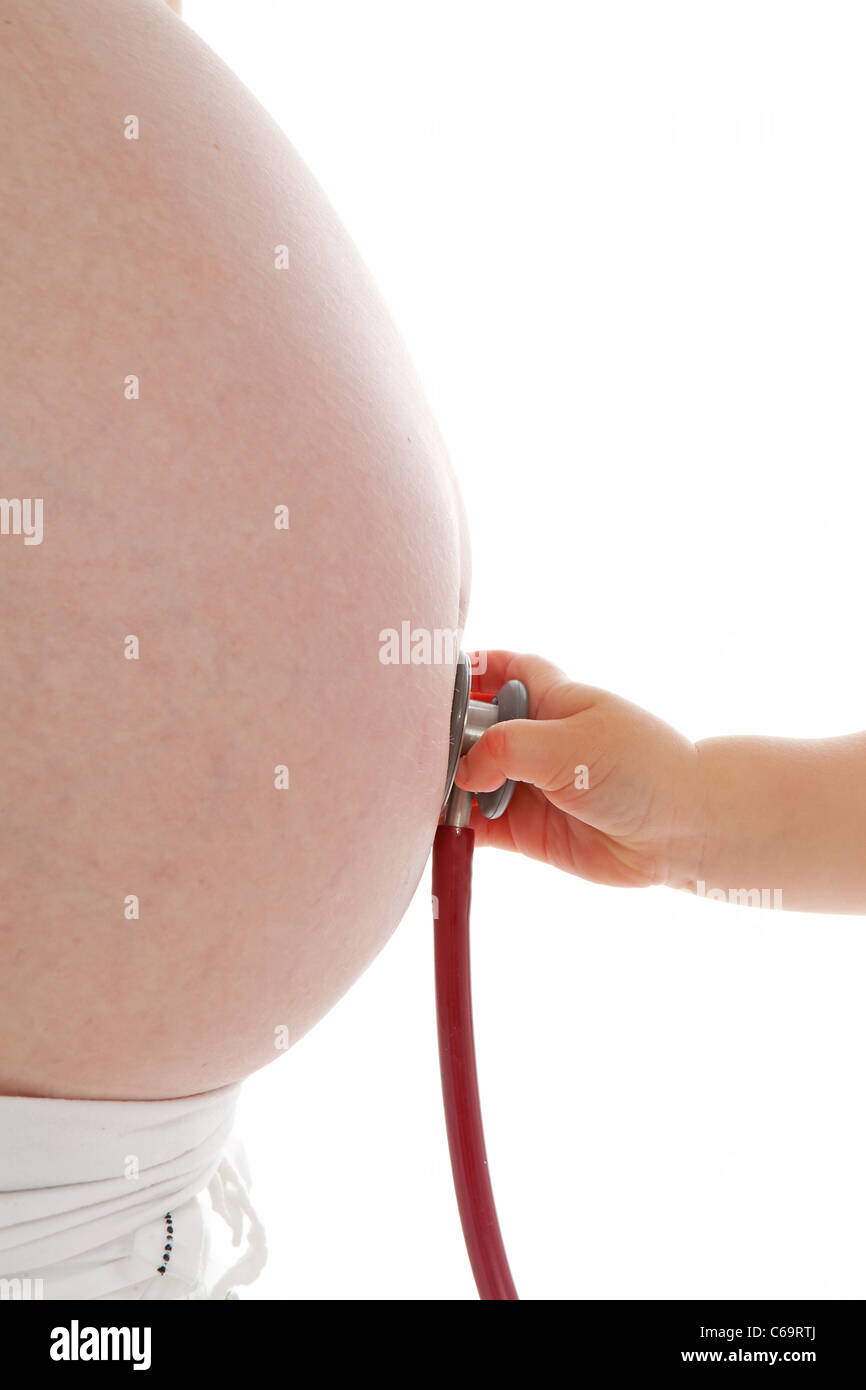 Children's hand with stethoscope on pregnant belly in closeup over ...