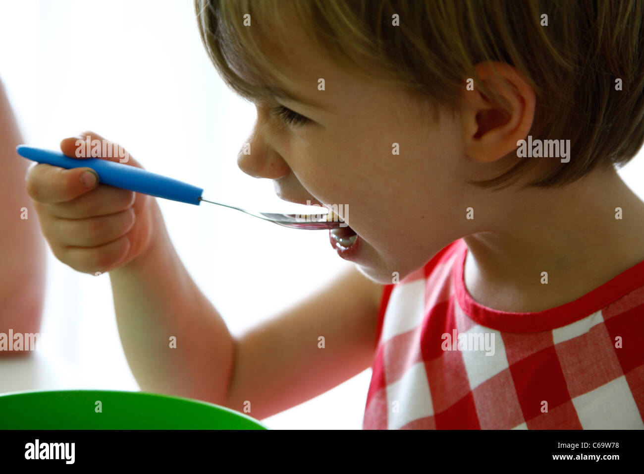 A young toddler eating with a spoon Stock Photo - Alamy