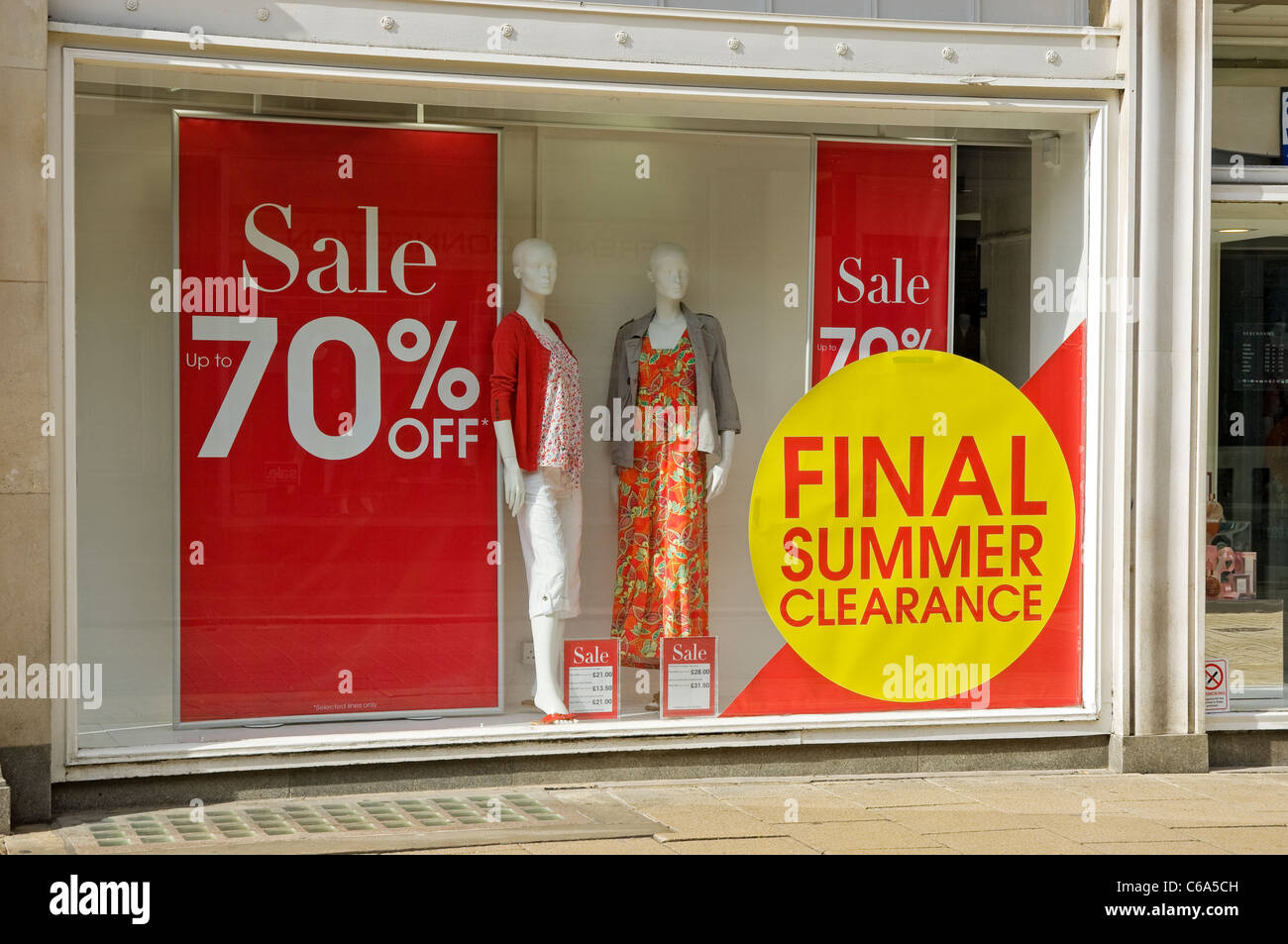 Sale signs sign signage in shop store window shopfront exterior England ...