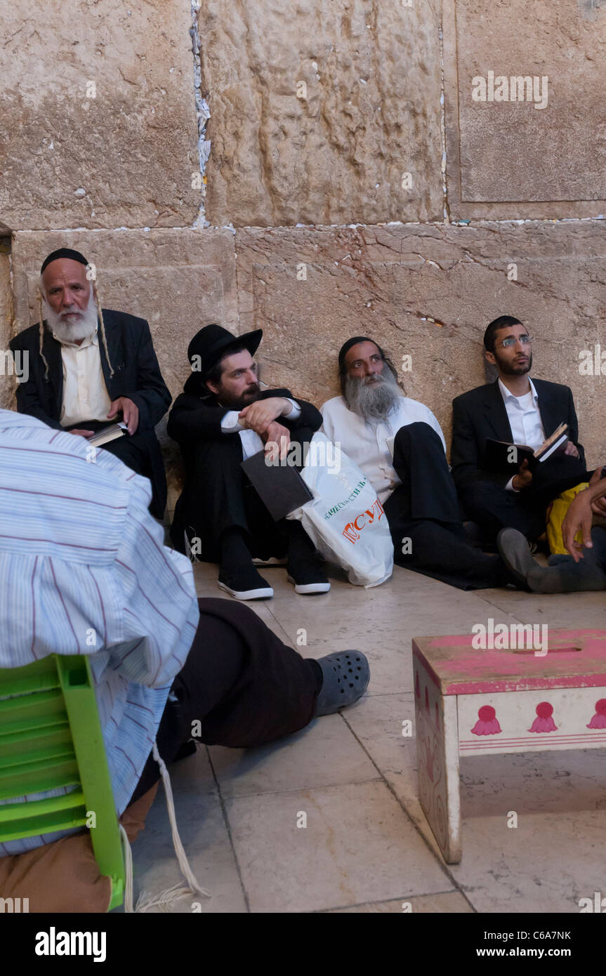 group of Jews sitting at Western Wall on Tisha Beav for the ...