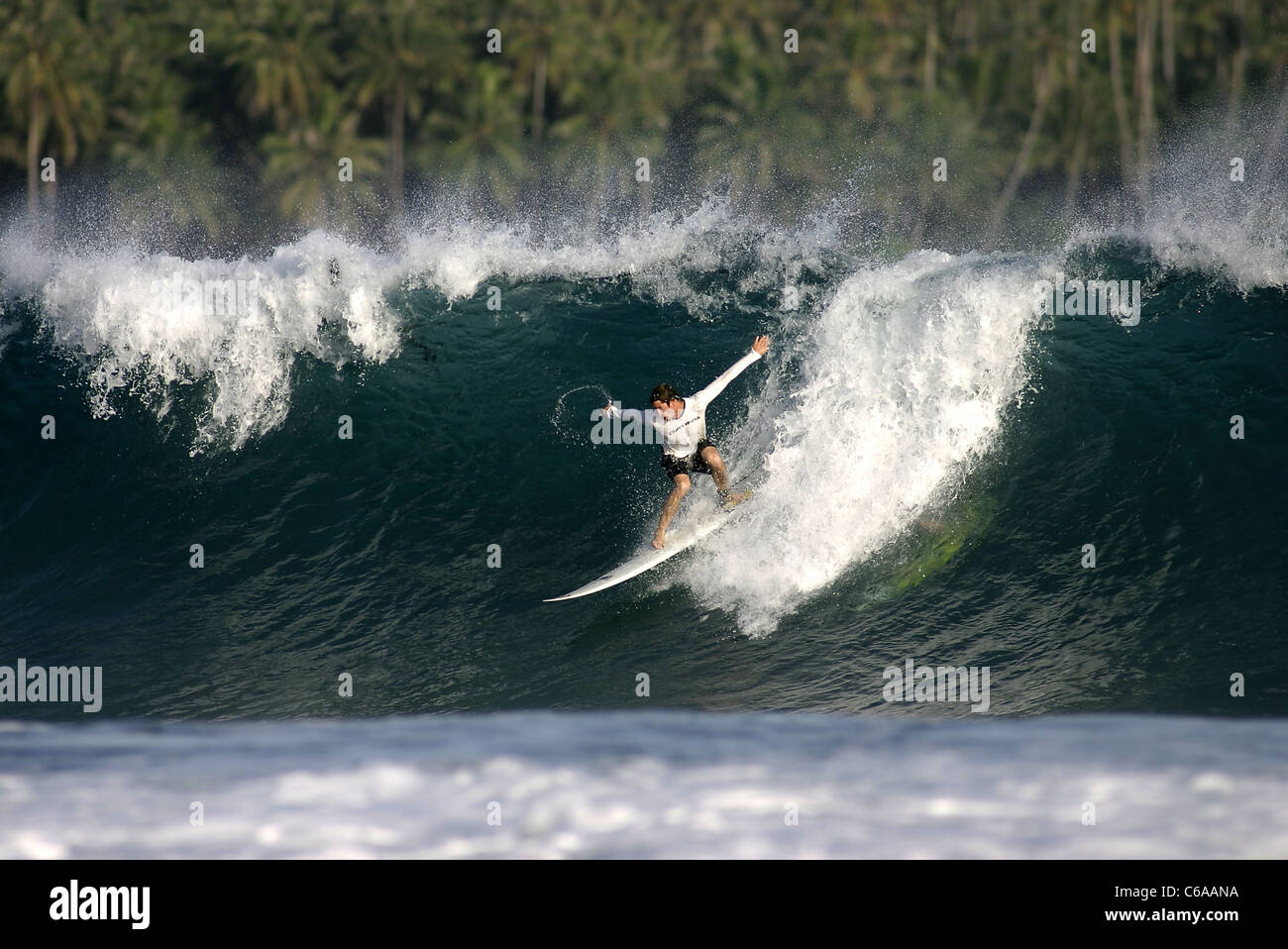 Traveling surfer riding a big wave. Sorake Beach, Lagundri Bay, Nias ...