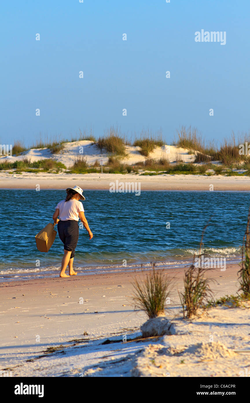 Woman collects shells on Crooked Island beach, a remote, empty beach ...