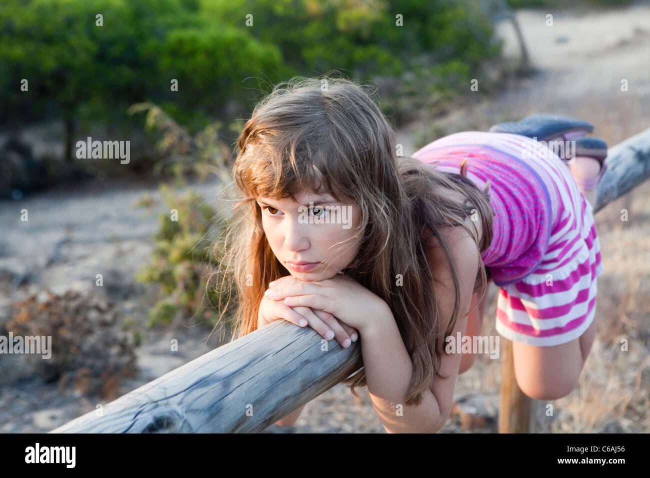 Profile of teenage girl with leaning on wood fence with faraway look ...