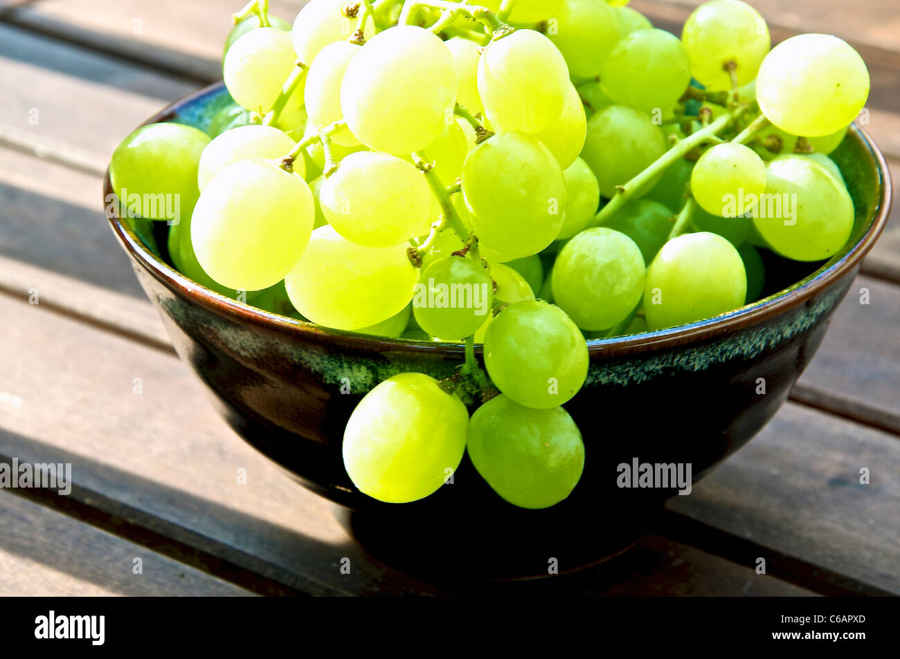 Sweet green grapes in a bowl on a sunny table Stock Photo - Alamy