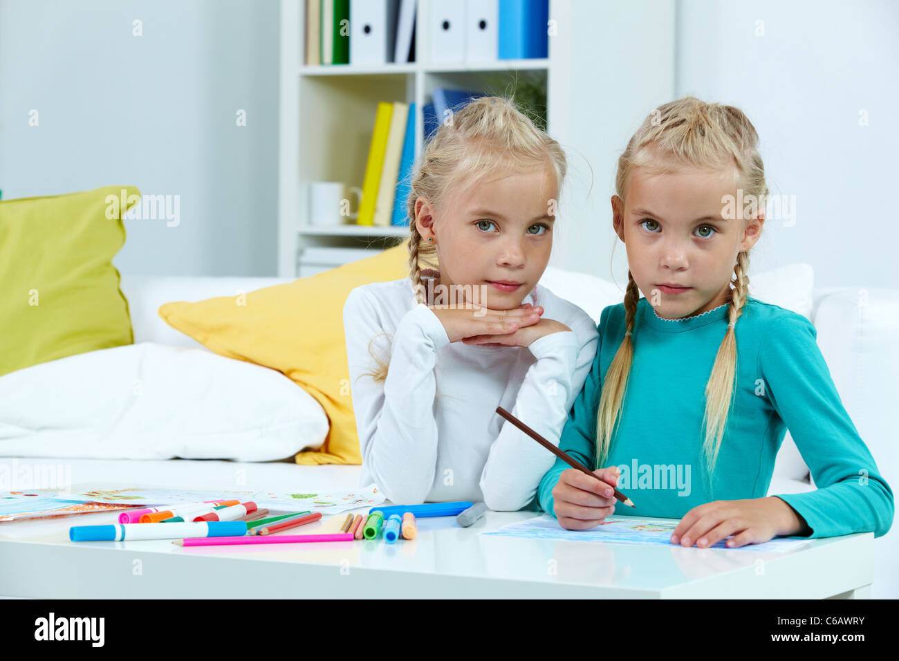 Portrait of lovely twins drawing with colorful pencils Stock Photo - Alamy
