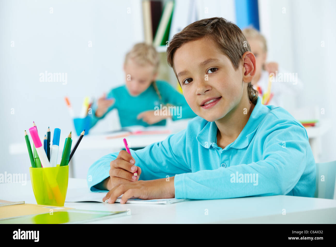 Portrait of cute lad drawing with classmates on background Stock Photo ...