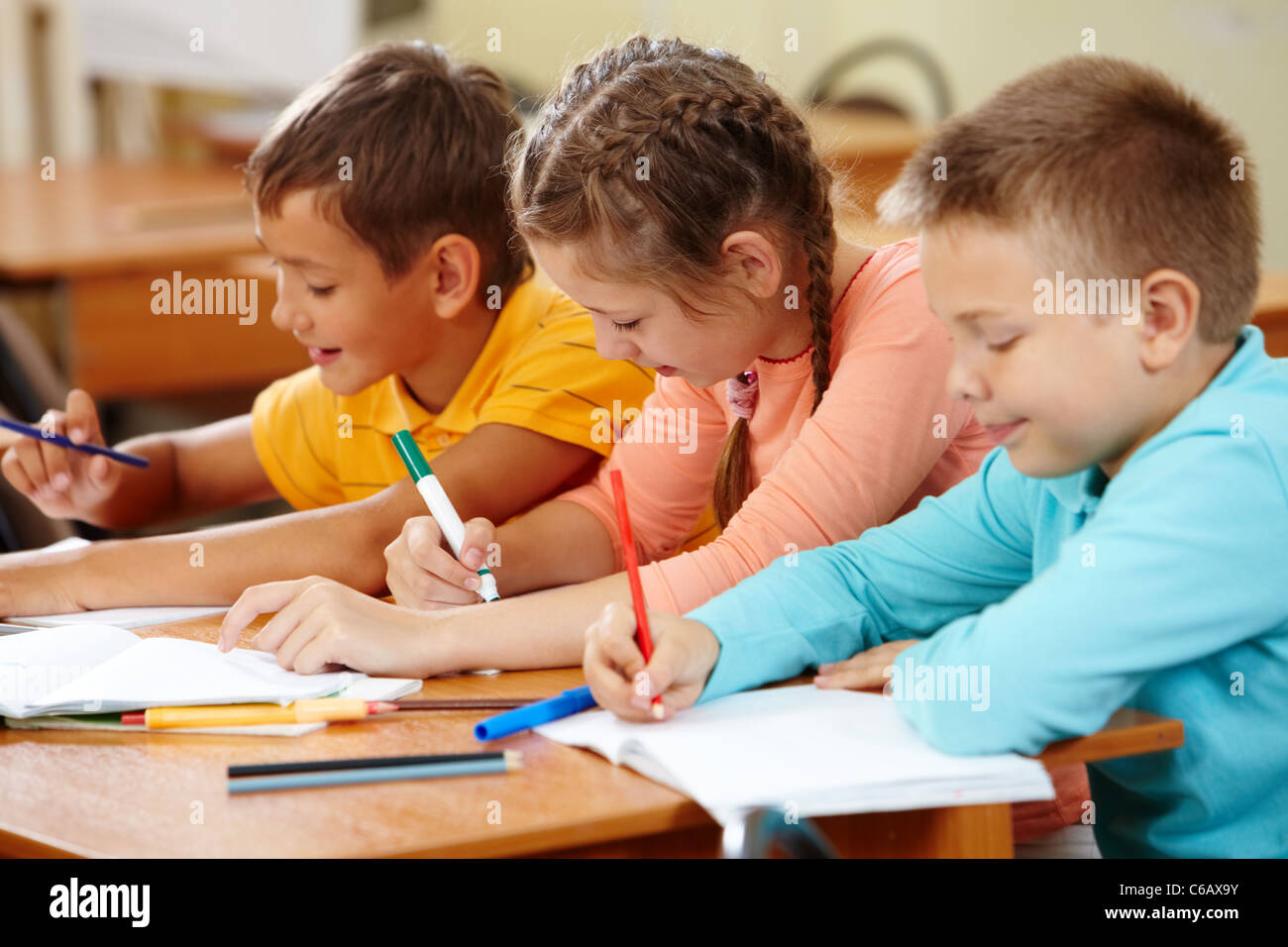Portrait of lovely girl and her classmates drawing with highlighters at ...