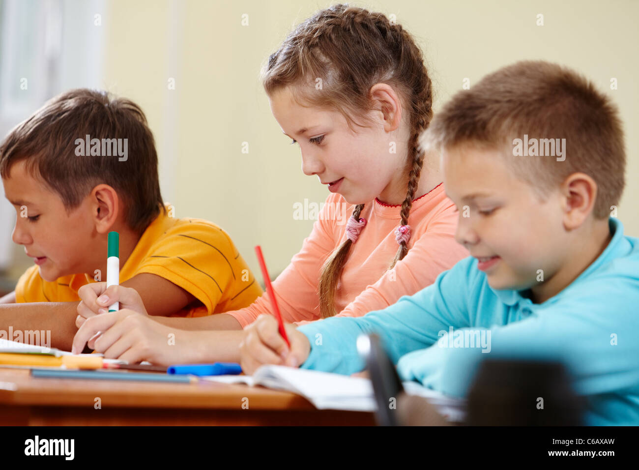 Portrait of lovely girl and her classmates drawing with highlighters at ...