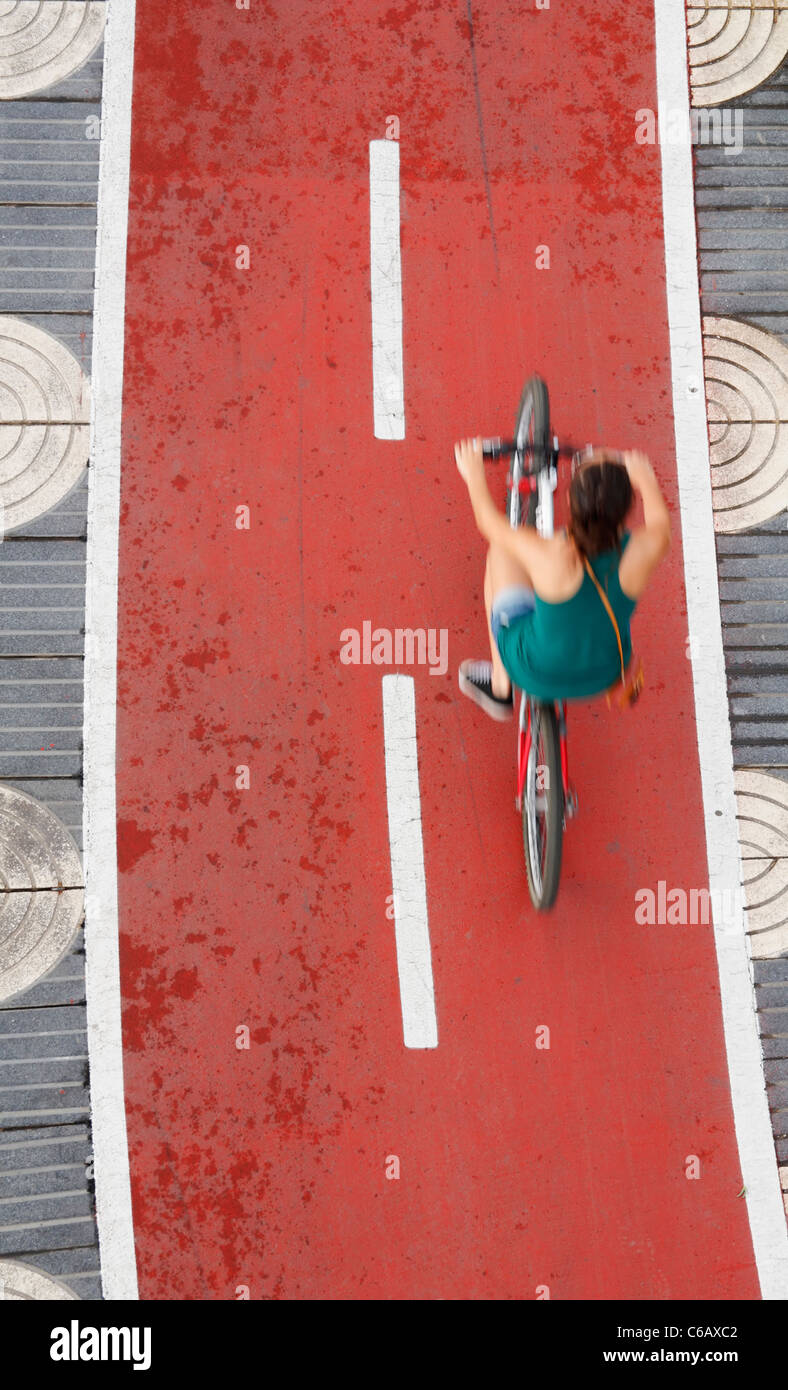 Overhead view of young woman riding bicycle on designated cycle path in ...