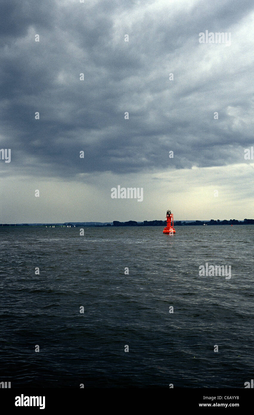 Orange coloured navigational buoy marking the shipping fairway on the ...