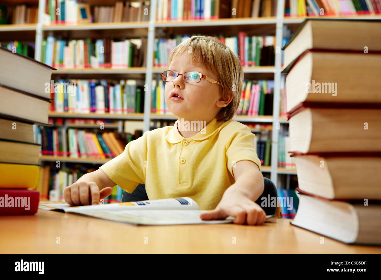 Portrait of interested schoolkid reading book in the library Stock ...