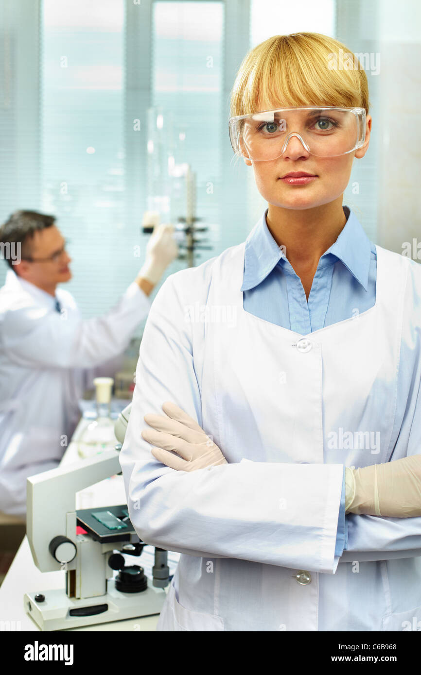 Portrait of a pretty scientist looking at camera against her working ...