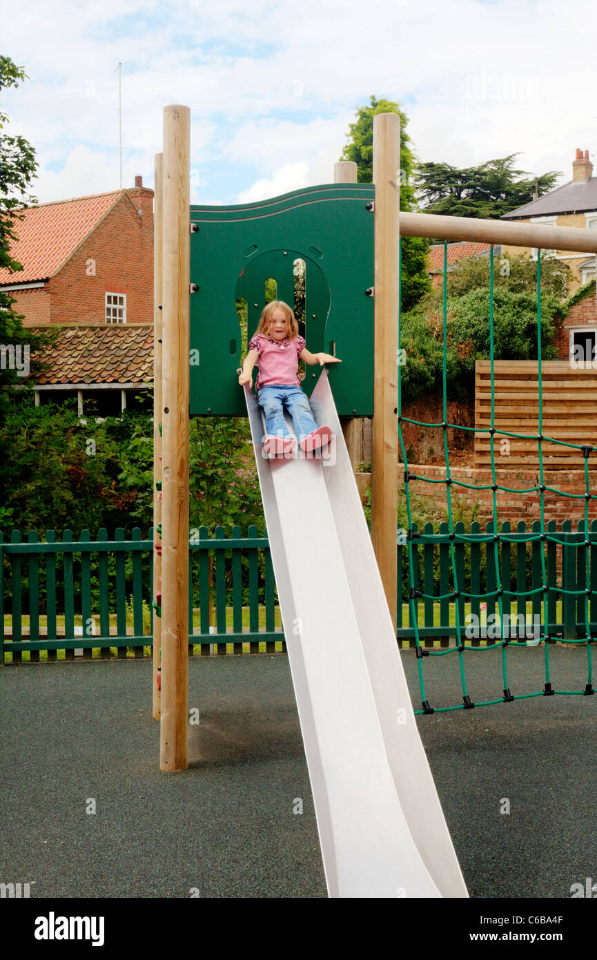 Young girl in playground on top of slide waiting to slide down in park ...