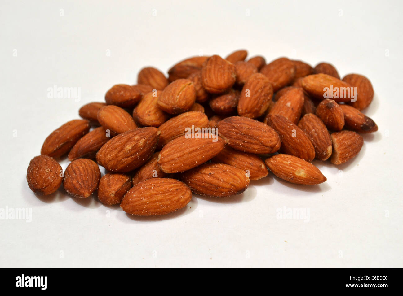 A pile of salted almonds lays on top of a plain wooded background Stock ...