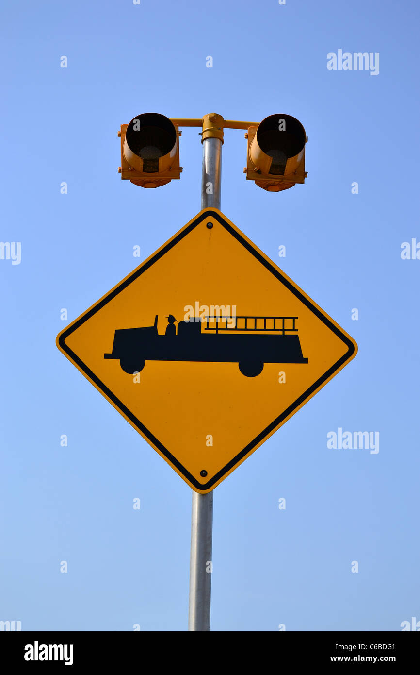A fire station warning sign with lights at the top on a pale blue sky ...