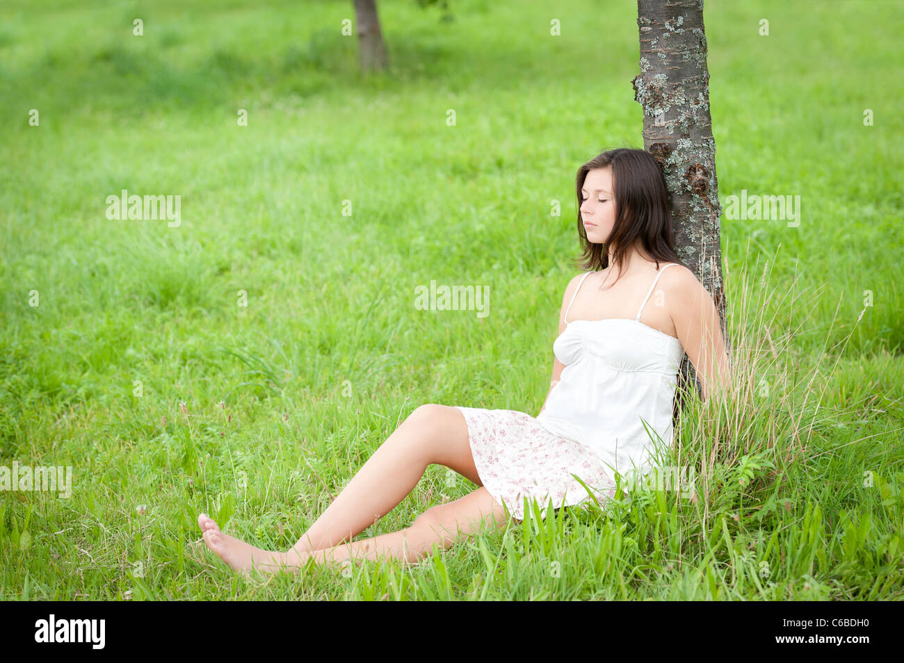 Outdoor portrait of a cute teen resting with closed eyes under a tree ...