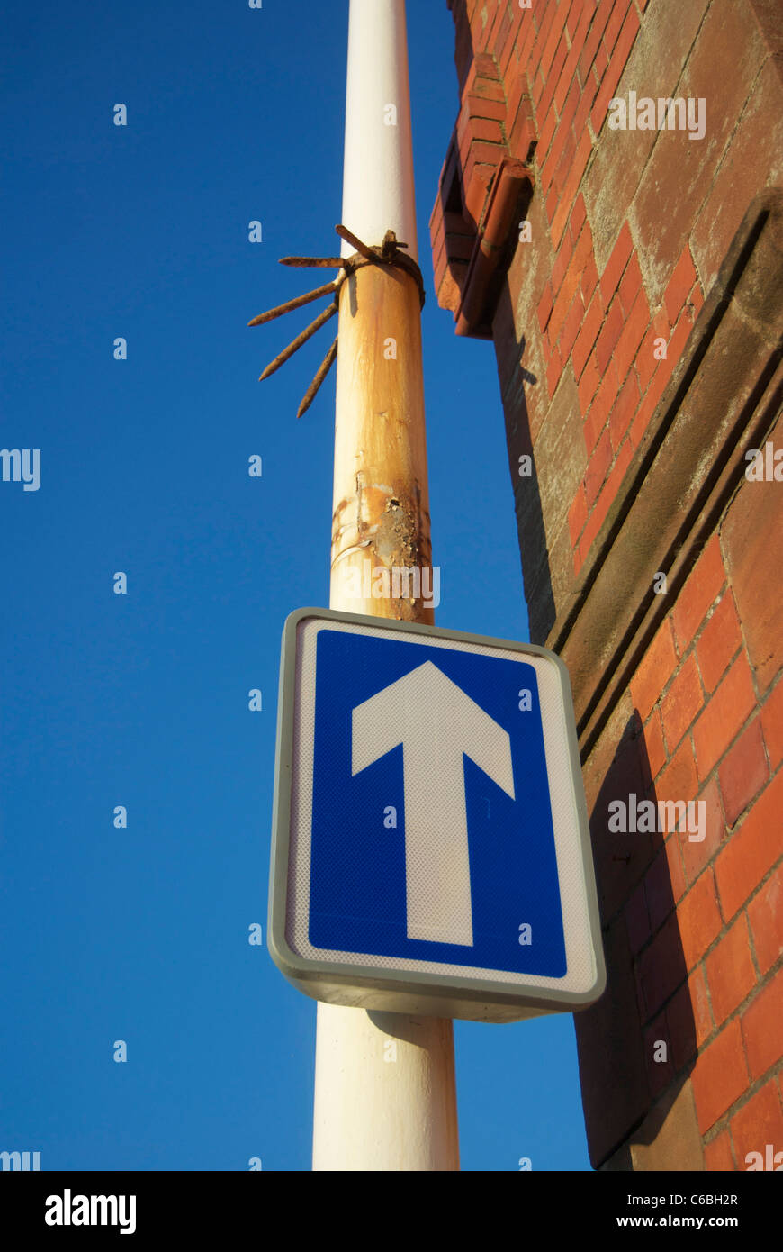 Sign pointing up on lamp post against blue sky Stock Photo - Alamy