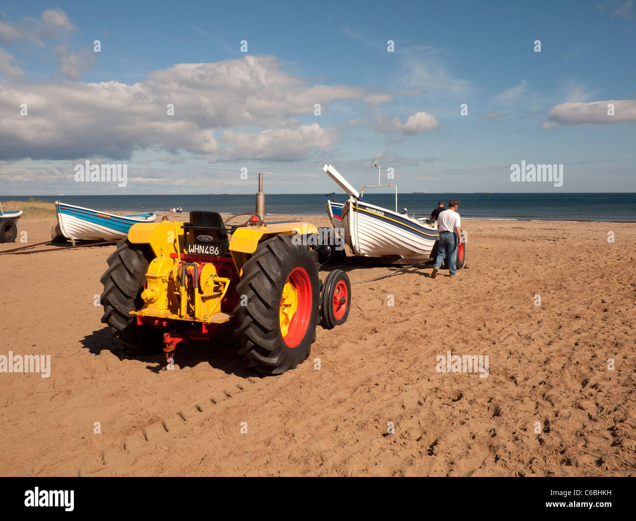 Fisherman's red and yellow tractor for launching boat from the beach ...