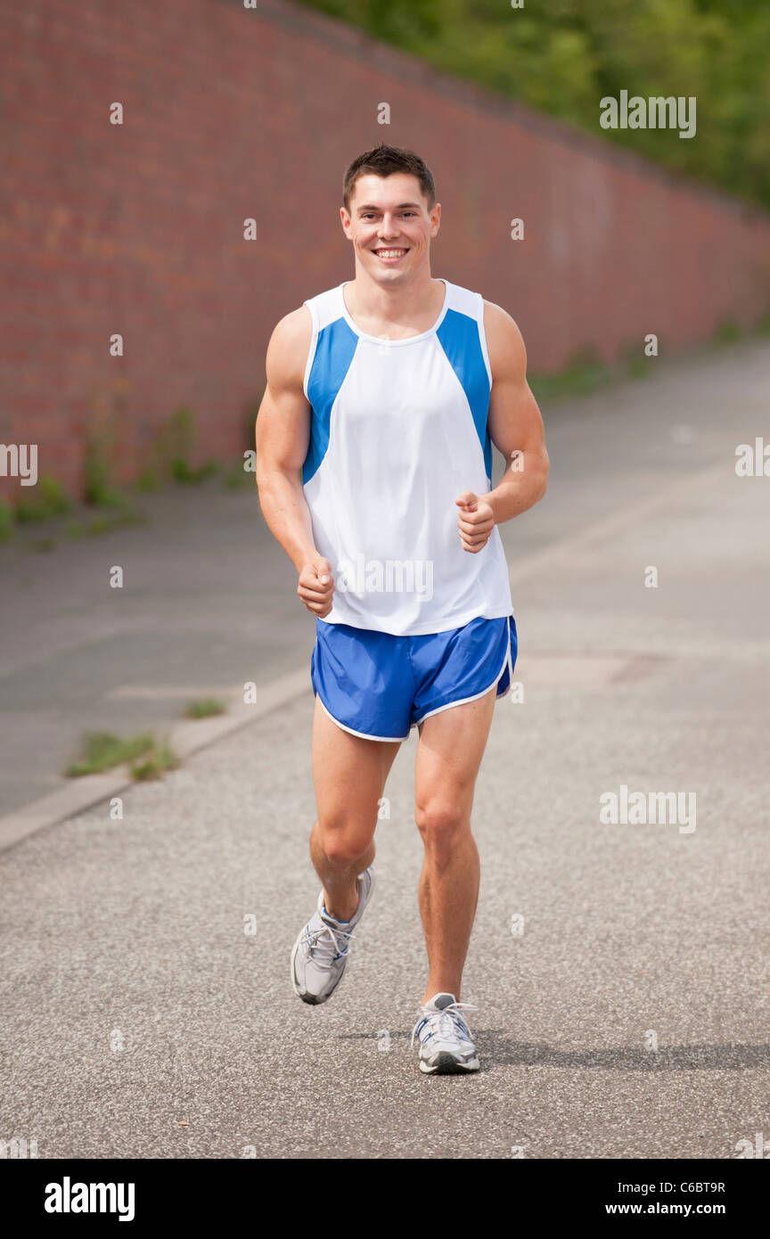 Young and smiling man running in the city Stock Photo - Alamy