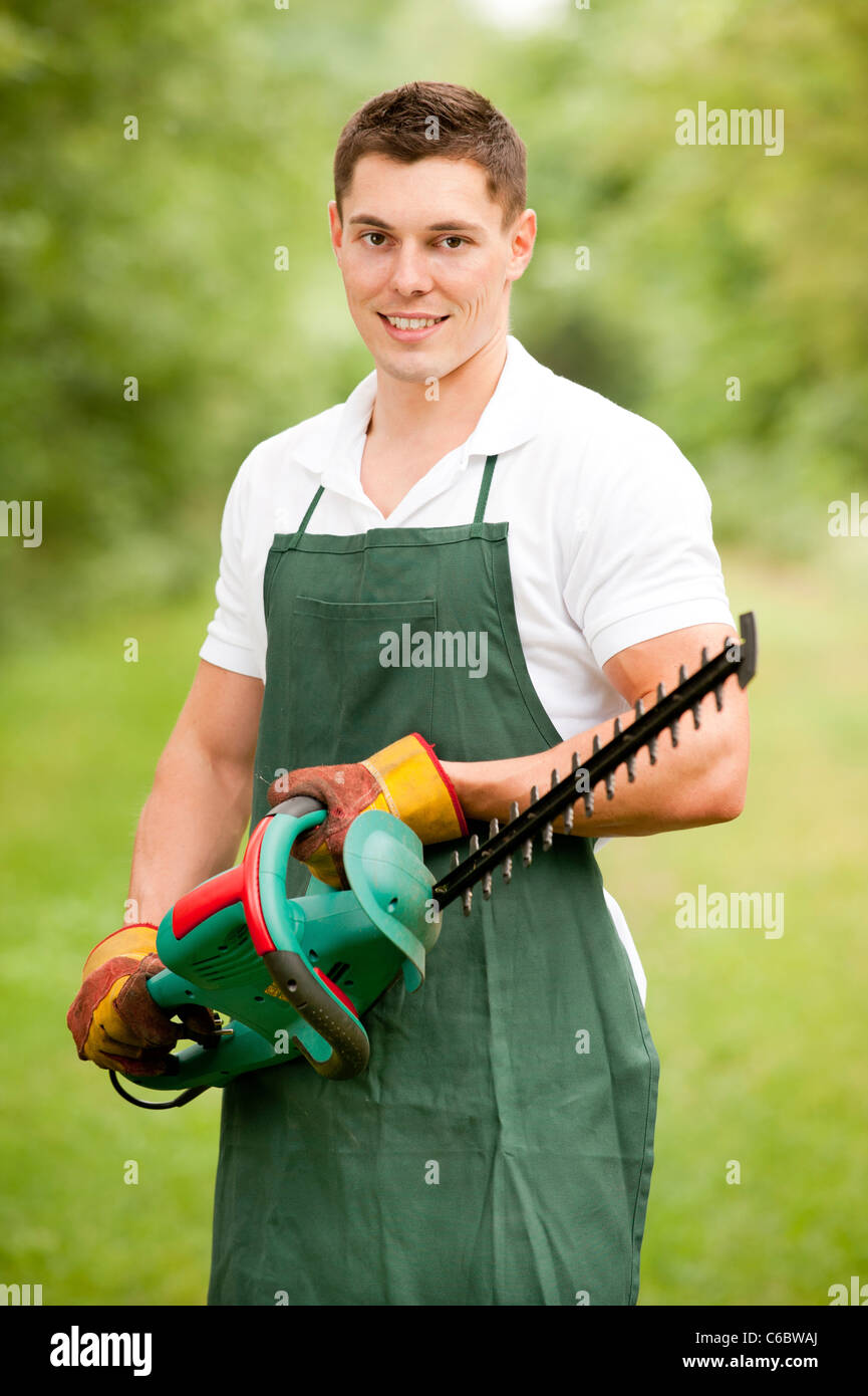 Young and smiling gardener with hedge cutter Stock Photo - Alamy