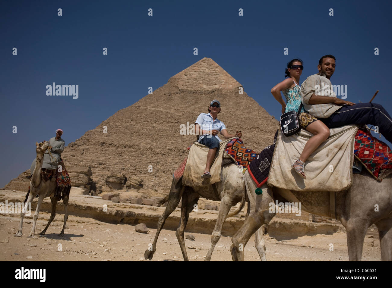 Tourists ride camels in front of the Kheops pyramid in Giza, near Cairo ...