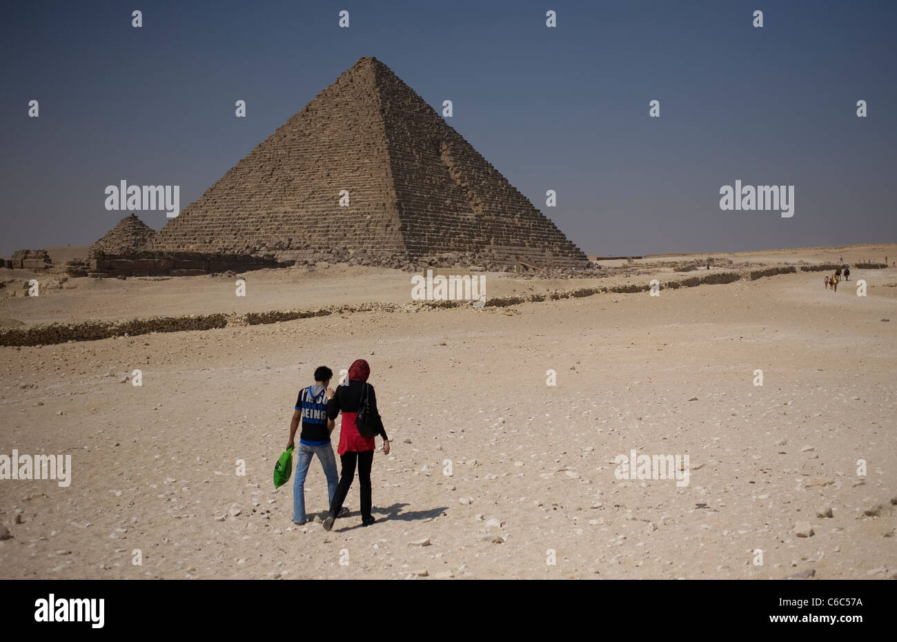 A tourist couple walk in front of Micerino pyramid in Giza, near Cairo ...