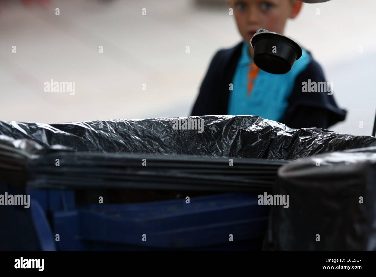Rubbish falling into a litter bin with a boy watching in the background ...