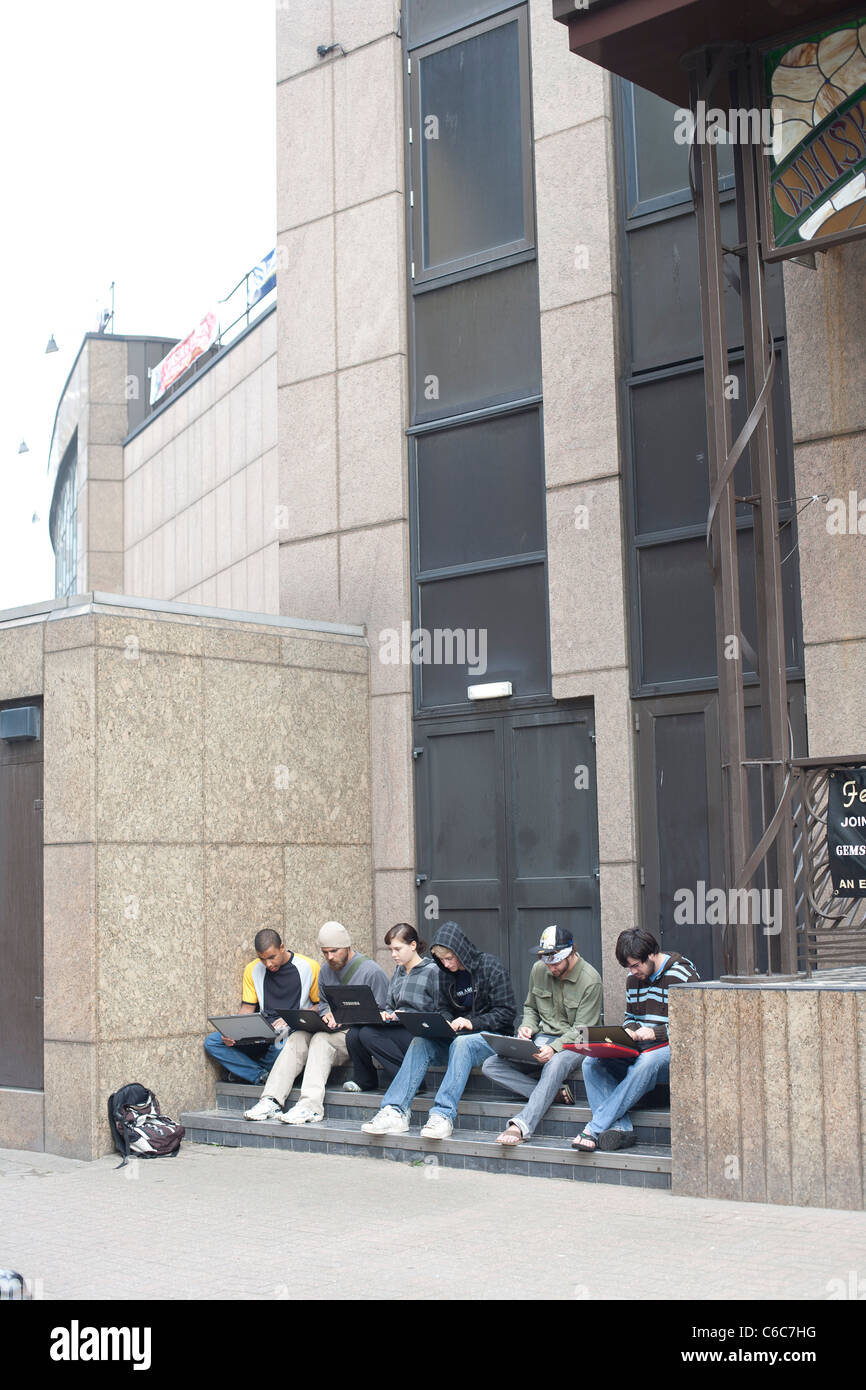A group of young people using their laptops after discovering a Wi-Fi ...
