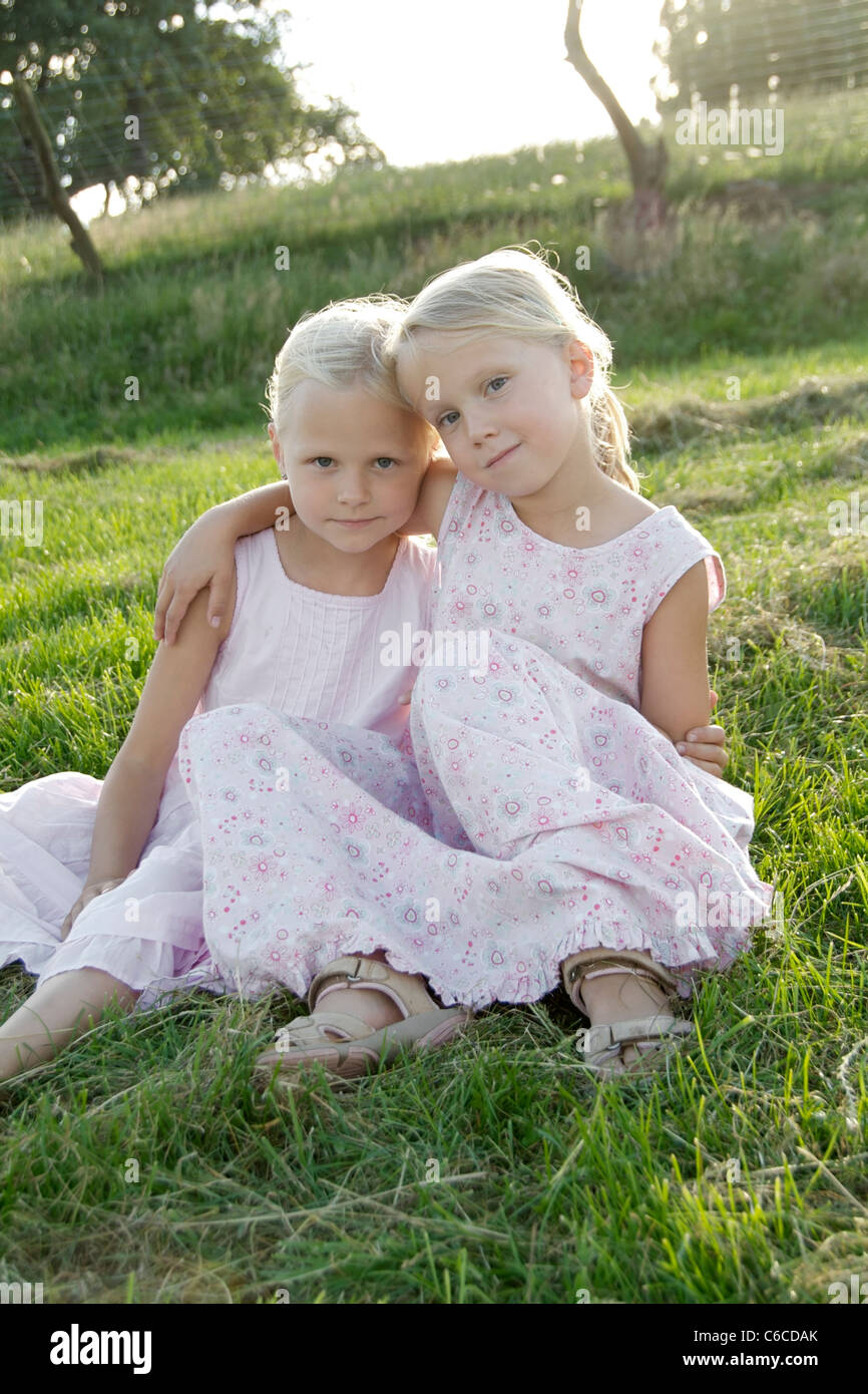 Portrait of two girl friends putting their arms around their shoulders ...