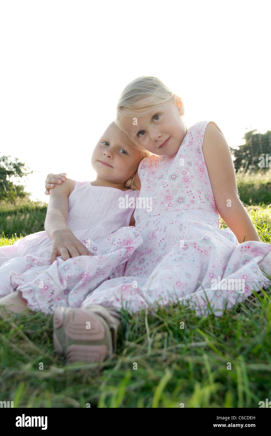 Portrait of two girl friends putting their arms around their shoulders ...
