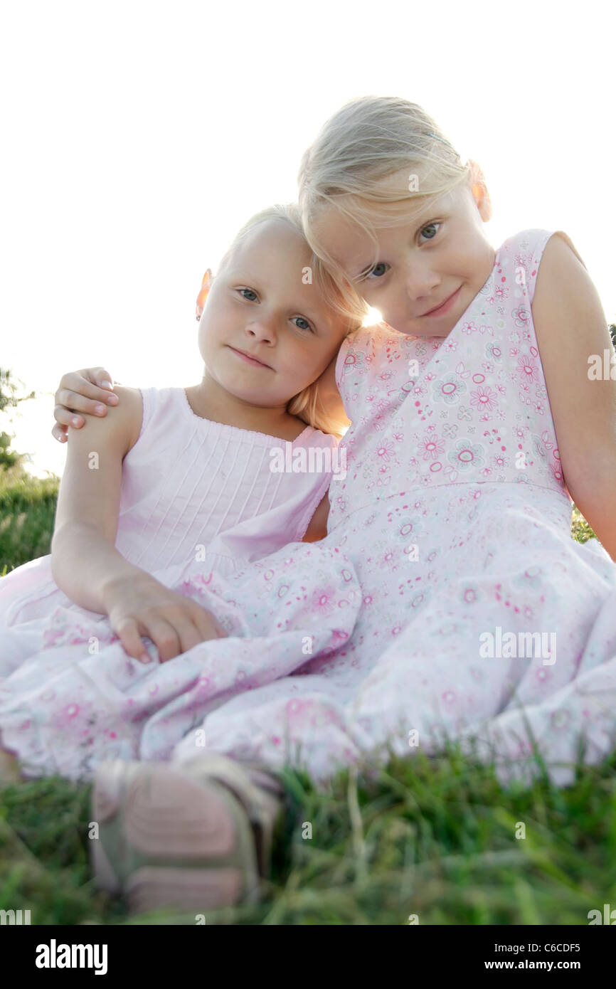 Portrait of two girl friends putting their arms around their shoulders ...