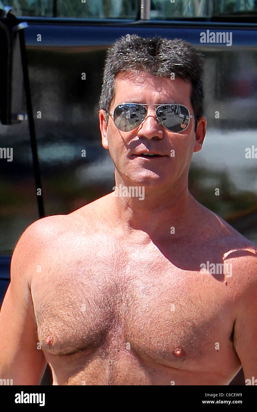 A shirtless Simon Cowell and his fiancee change boats in the port of ...