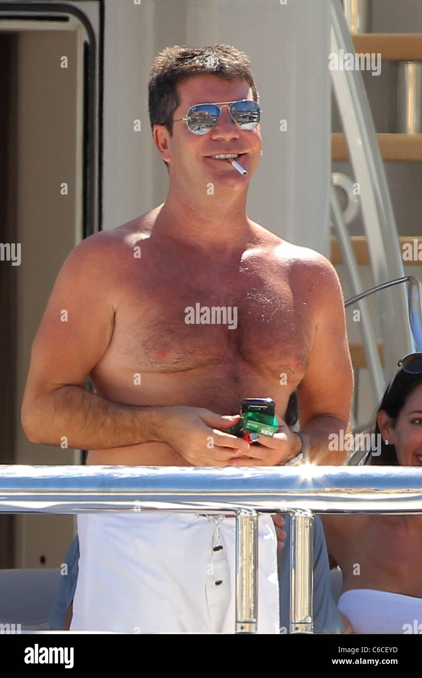 A shirtless Simon Cowell and his fiancee change boats in the port of ...