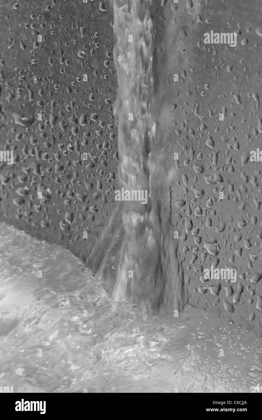water flow over metallic wall into pool with water drops and bubbles ...