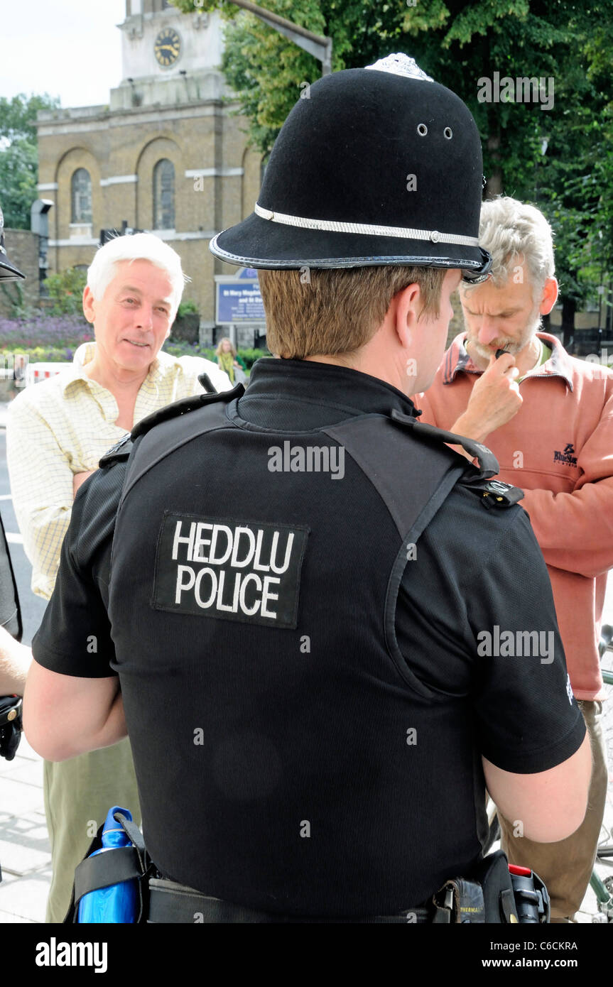 Rear view of a Welsh or Heddlu police officer talking to local ...