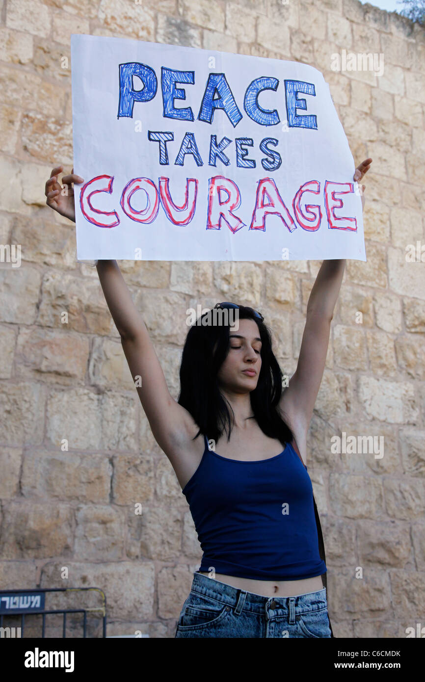 An Israeli peace activist holds a paperboard sign which reads Peace ...