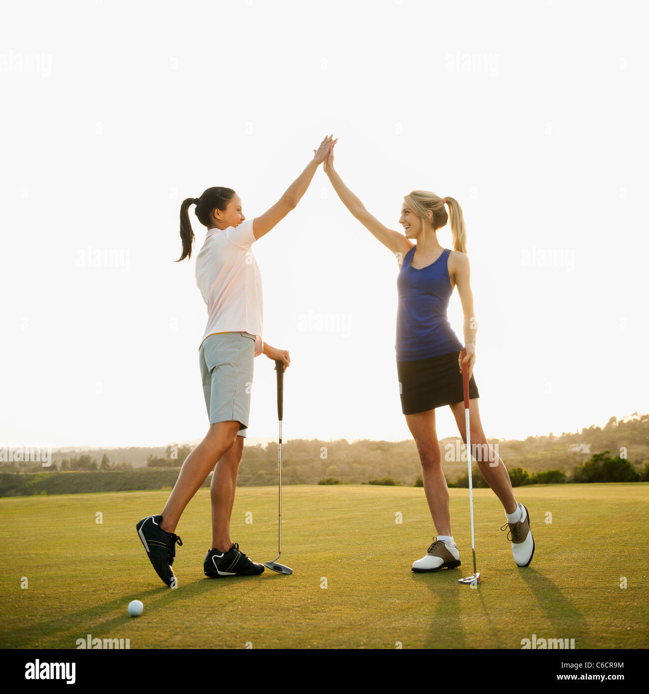 Women golfers high fiving on golf course Stock Photo - Alamy
