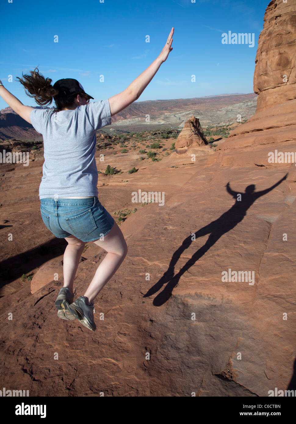 Moab, Utah - A young woman dances with her shadow on slickrock in ...