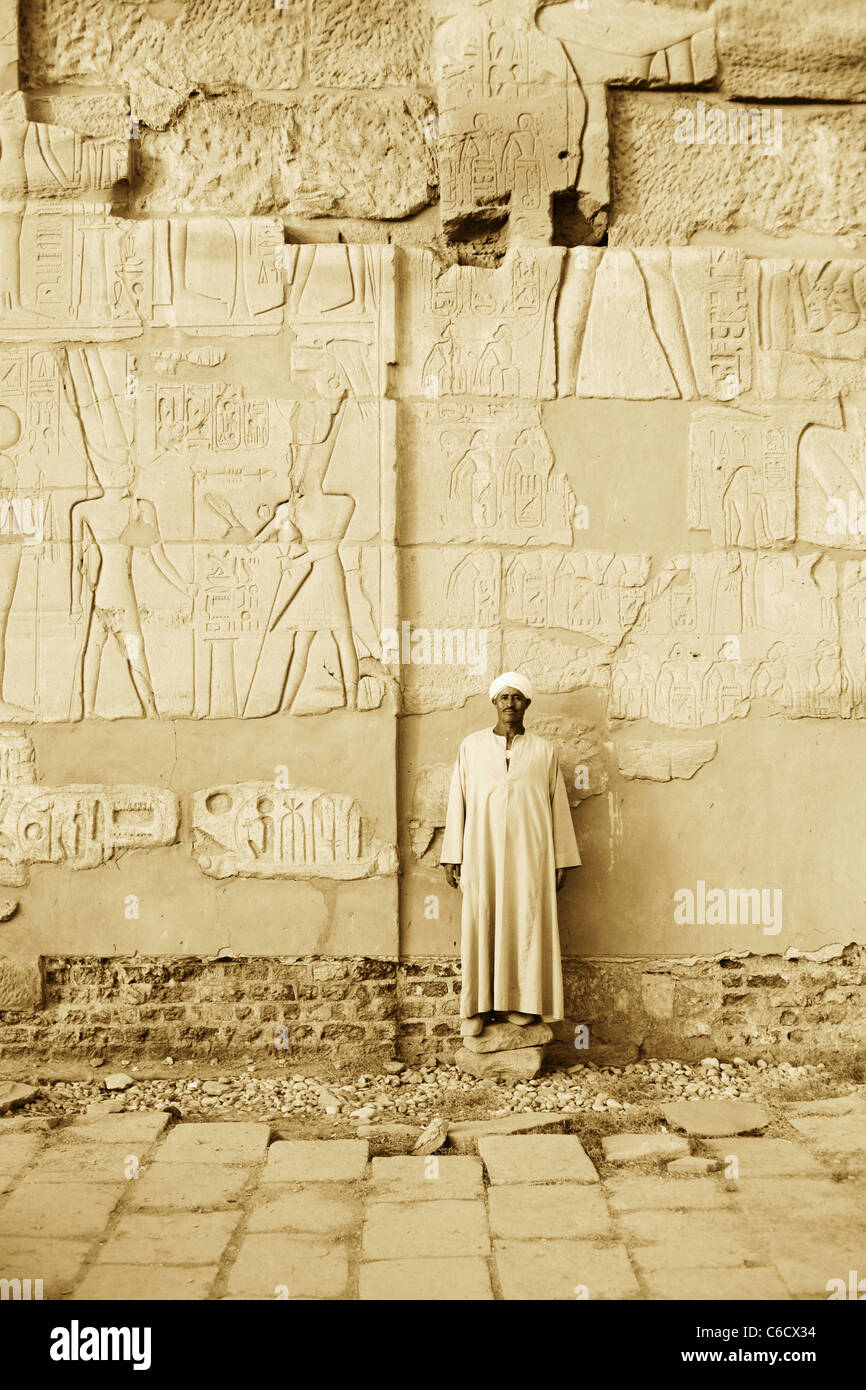 An Egyptian man in traditional garb poses in front of a wall of ...