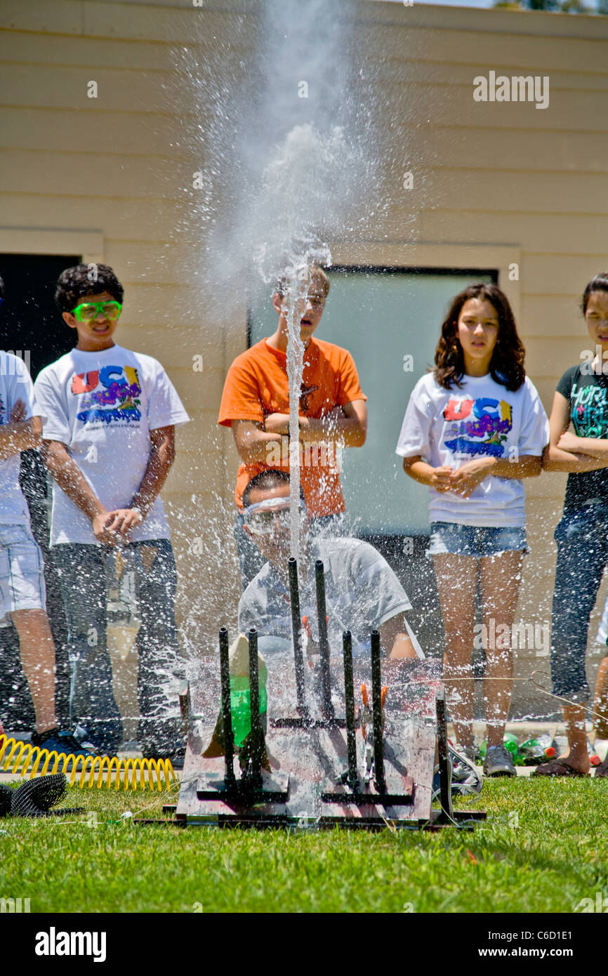 Teen students watch as a teacher launches an air-and-water-powered ...