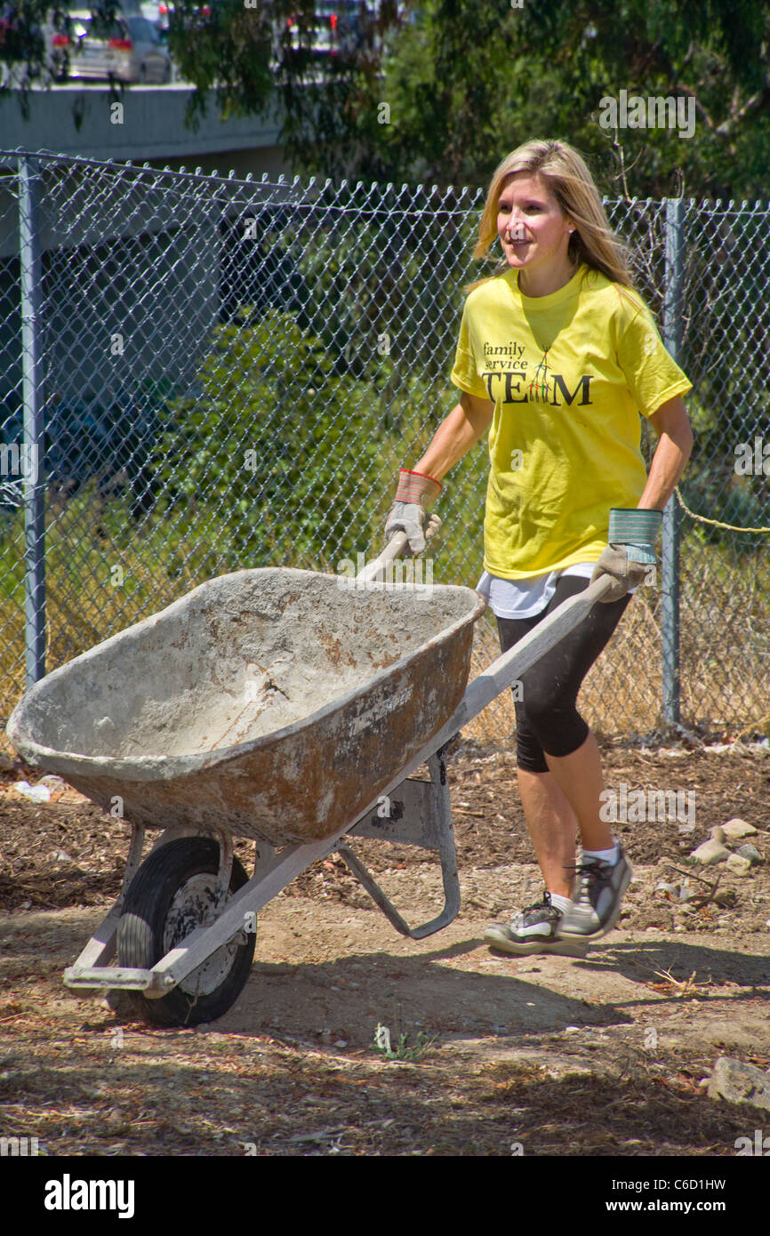 A woman volunteer pushes a wheelbarrow at an urban renewal project in ...