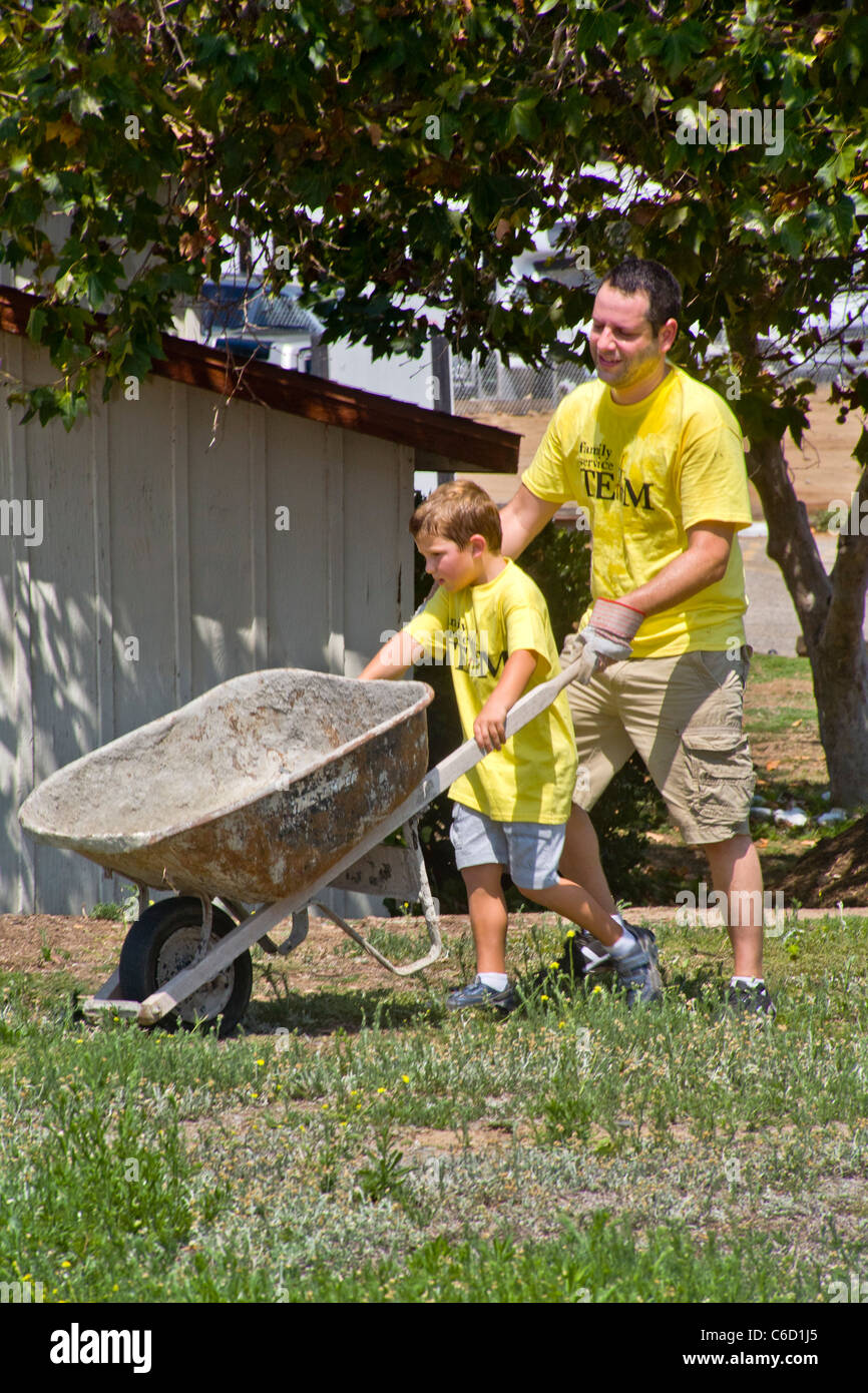 Father and son share the task of pushing a wheelbarrow at a volunteer ...